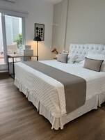 Quarto moderno com uma cama grande, uma escrivaninha e uma cadeira.