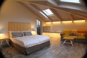 Quarto com cama, sofá e claraboia.