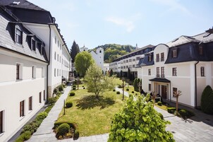 Um pátio com edifícios brancos, uma árvore central e um caminho.