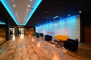 Um lobby moderno com piso xadrez, balcão de recepção e área de estar com sofás e mesa de centro.