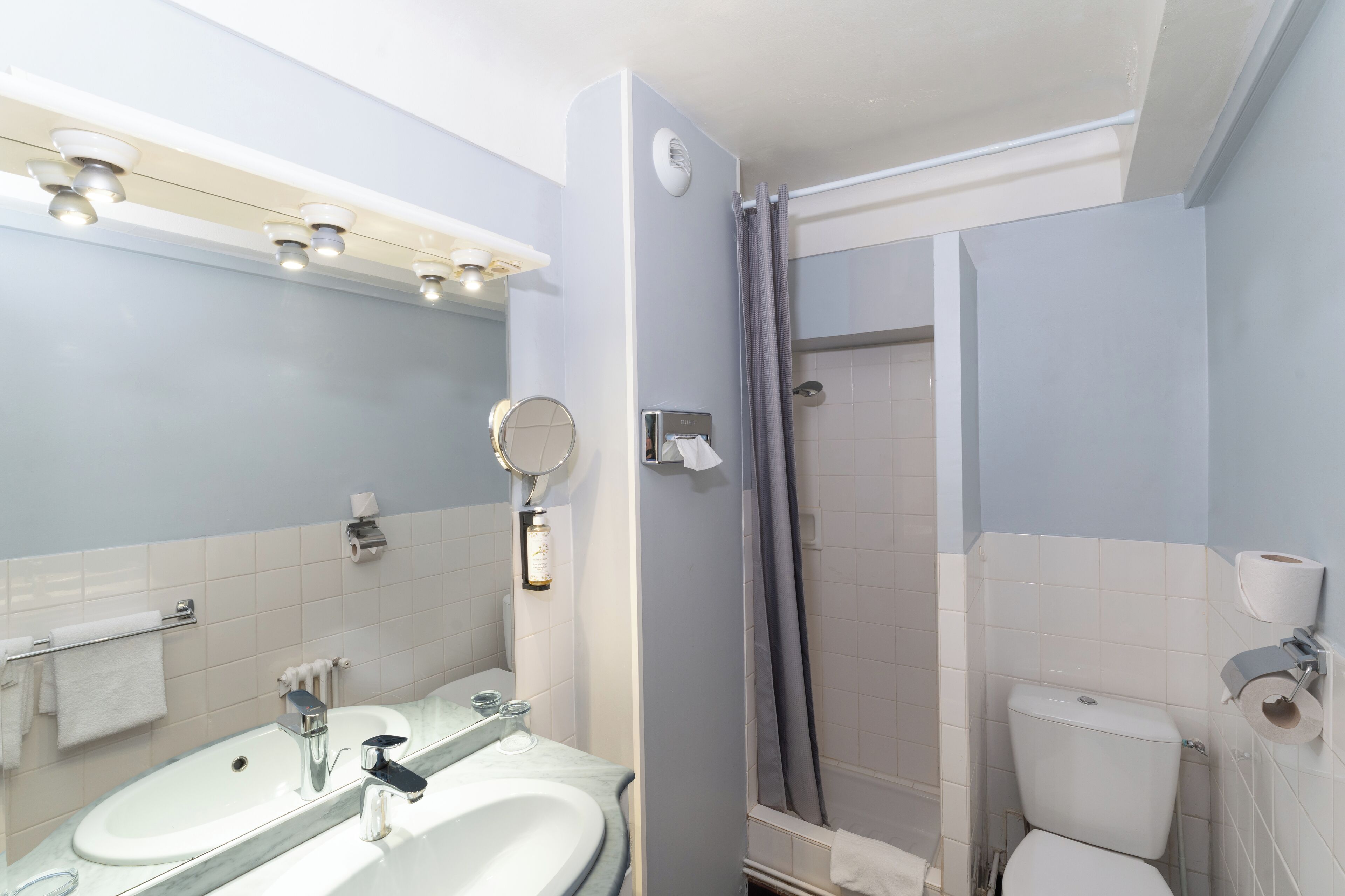 Uma casa de banho moderna com uma sanita de duas cubas, um espelho grande, uma sanita e uma área de duche.