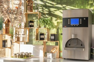 Cozinha moderna com máquina de café expresso embutida, prateleiras de madeira com utensílios de cozinha e uma planta em vaso.