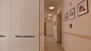 Um corredor de hotel com placas indicando 'HOTEL ARKADIA 2' e 'DIA 2'.