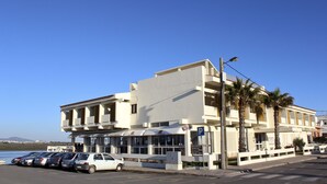 Um hotel com vários andares, estacionamento e vista para o mar.