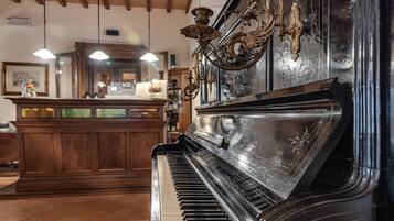 Um piano de cauda em um ambiente bem iluminado, com lambris de madeira e decoração na parede.