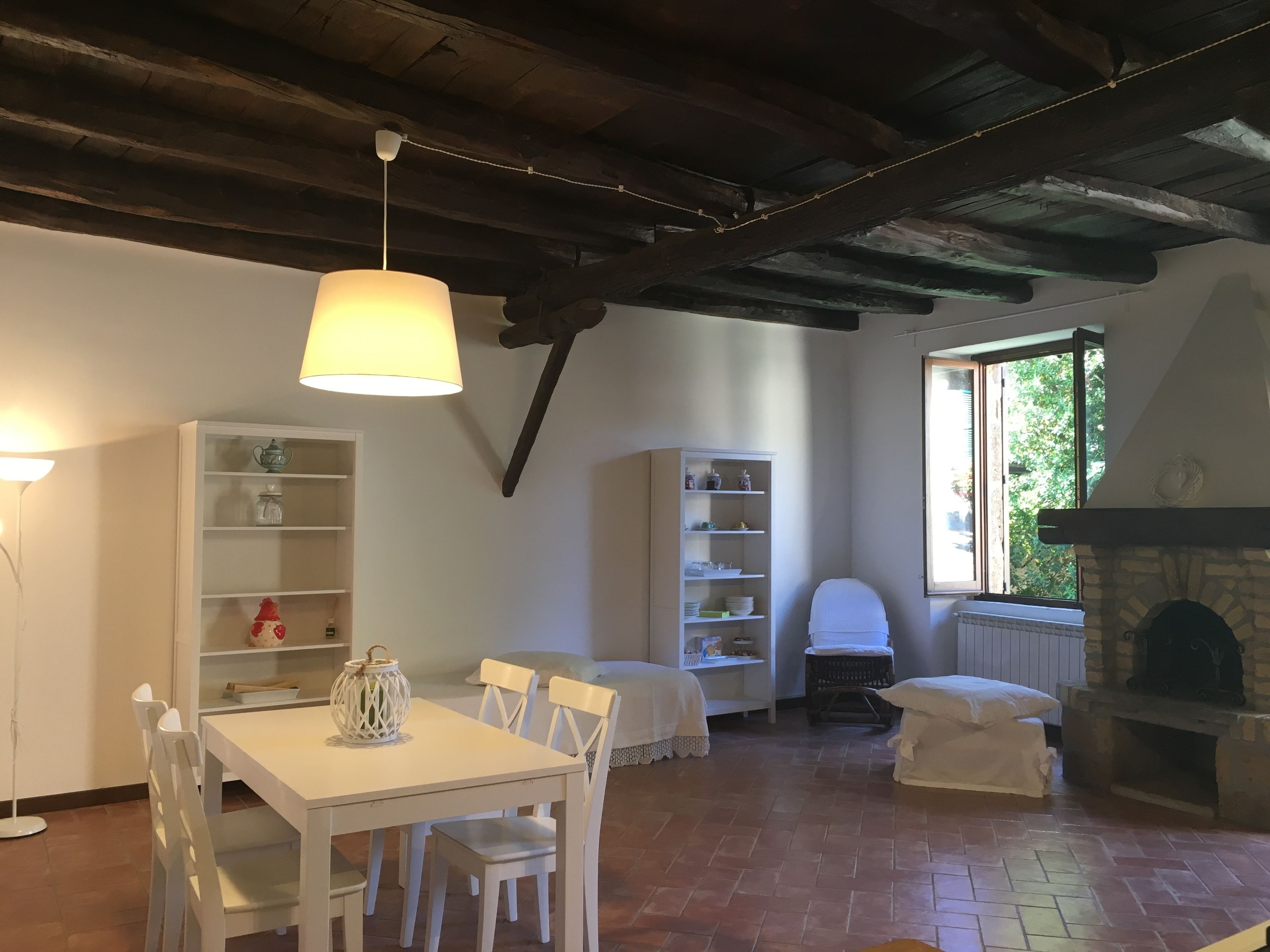 Uma área de refeições com uma mesa e cadeiras brancas, um lustre pendurado e uma lareira.