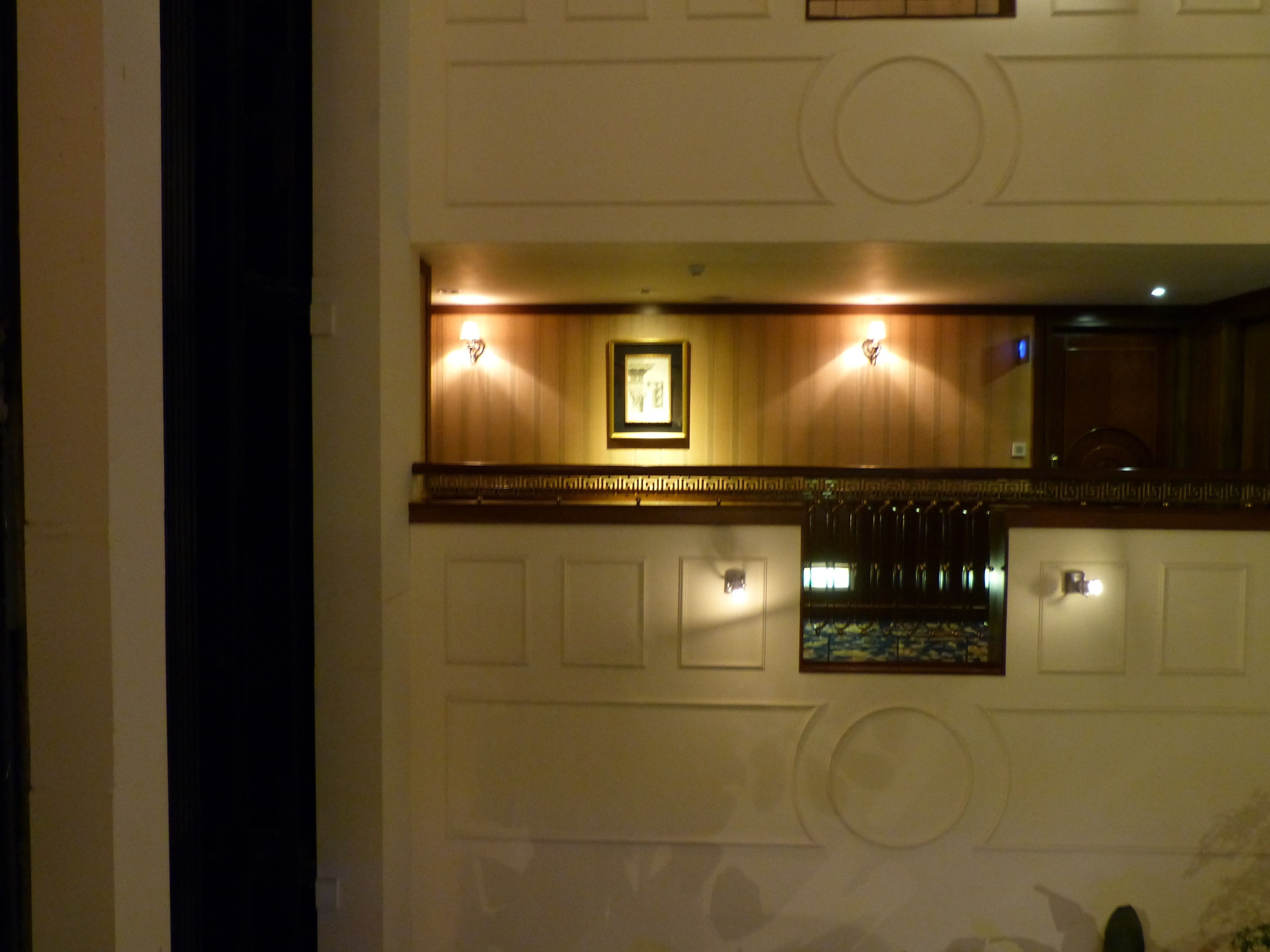 Um hall de hotel com área de bar, obras de arte emolduradas e luminárias fixadas na parede.