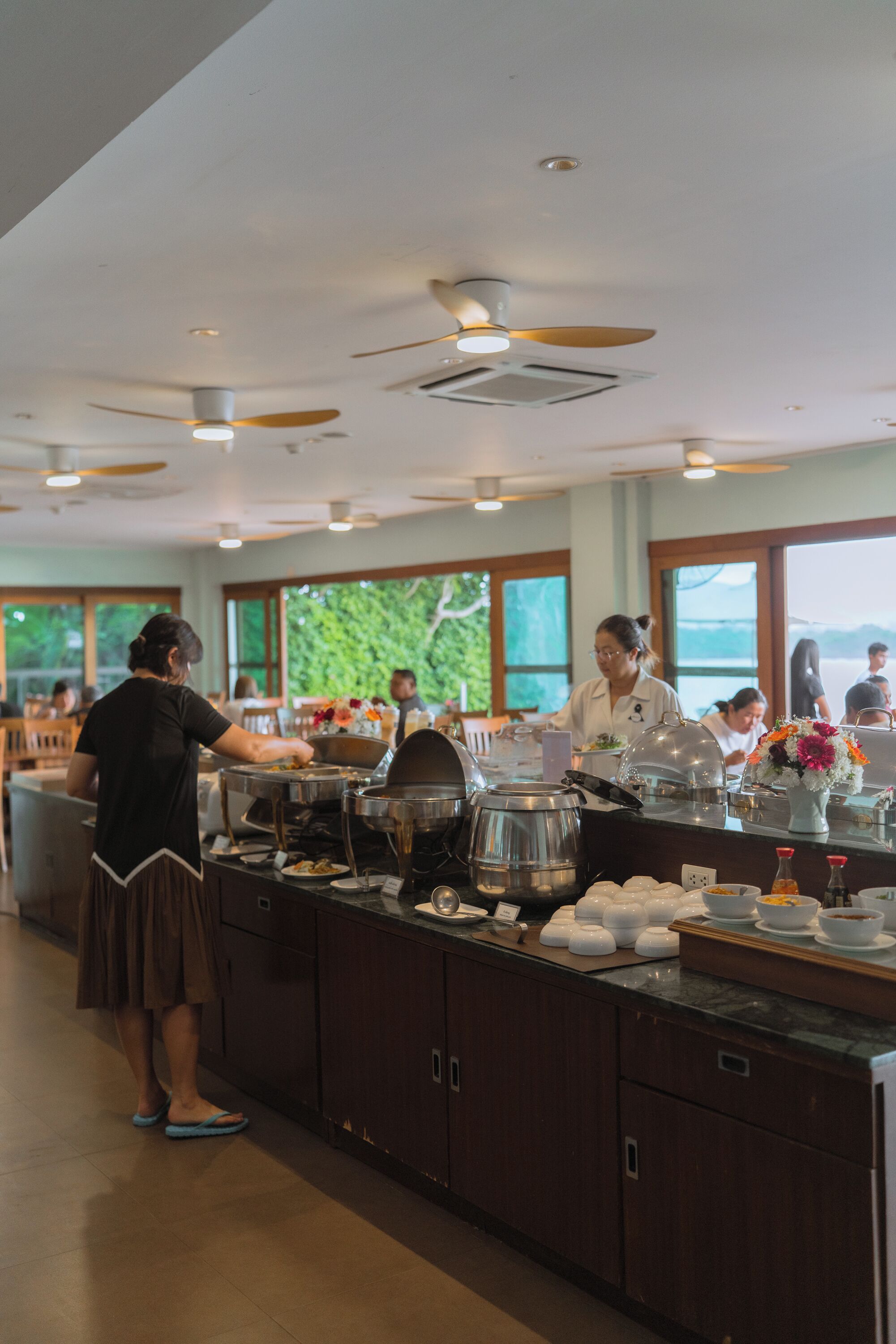 Uma área de buffet com balcão, recipientes de comida e um atendente.
