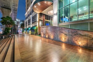 Um hall de hotel moderno com piso de madeira, grandes janelas e uma parede decorativa.