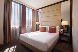 Quarto de hotel com uma cama grande, duas luminárias de cabeceira, uma mesa de cabeceira e um espelho.
