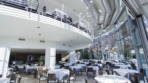 Um restaurante espaçoso com várias áreas de refeições, um espaço central aberto e uma varanda com vista para o interior.