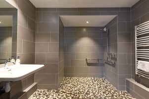 Um banheiro moderno com chuveiro, pia e piso revestido de azulejos.