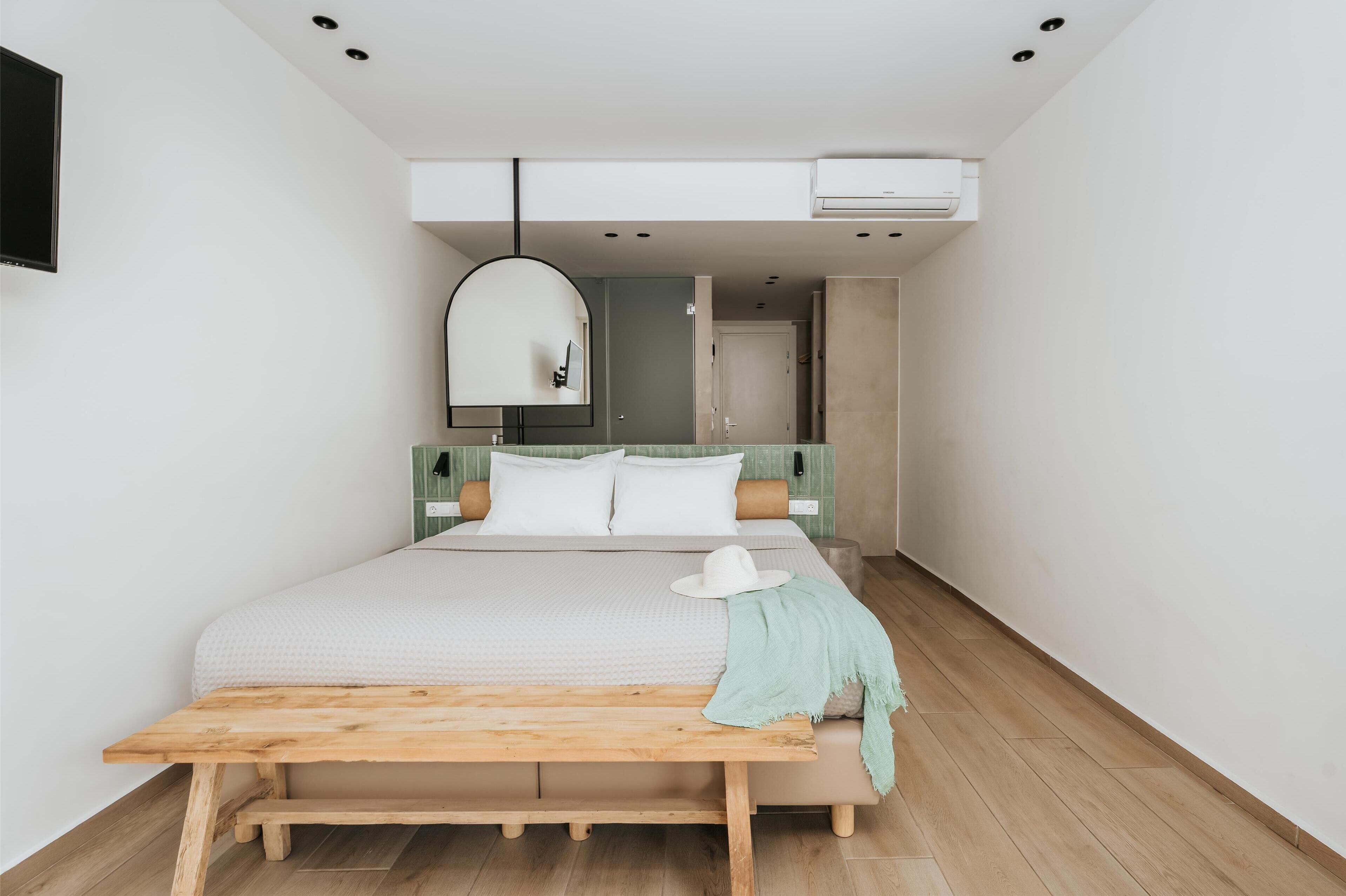 Quarto moderno com cama de madeira, mesa de cabeceira, espelho e luminária pendente.