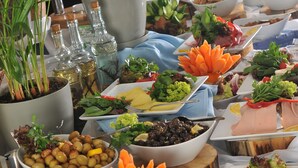 Mesa de buffet com diversos pratos e um vaso de planta.