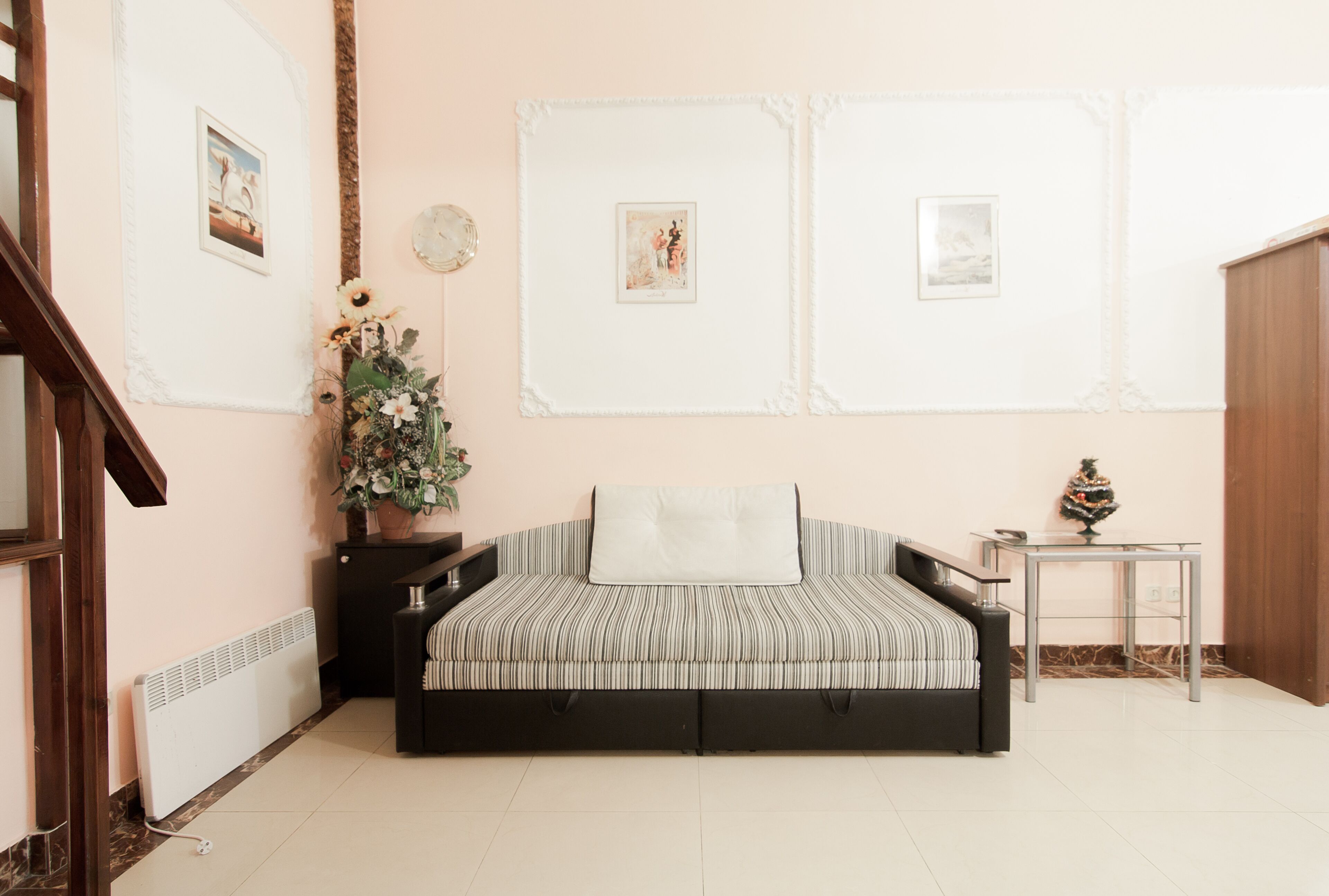 Um quarto acolhedor com um sofá listrado, uma mesa pequena, uma planta decorativa e quadros nas paredes.