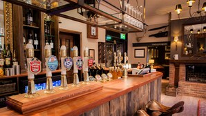 Um bar com várias torneiras de cerveja, um balcão de madeira e botas de couro.