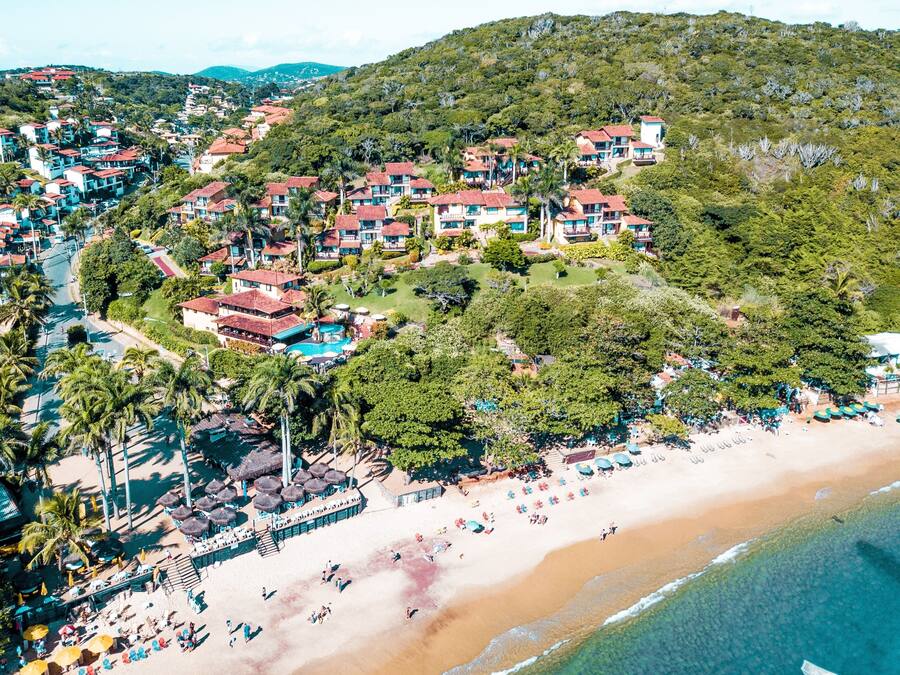 Vista aérea de um resort costeiro com vários edifícios, uma praia e uma piscina.