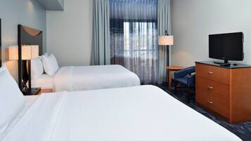 Quarto de hotel com duas camas, televisão, escrivaninha e cómoda.