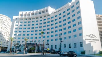Hotel de vários andares com design arquitetônico moderno, apresentando um logotipo bem visível na fachada.