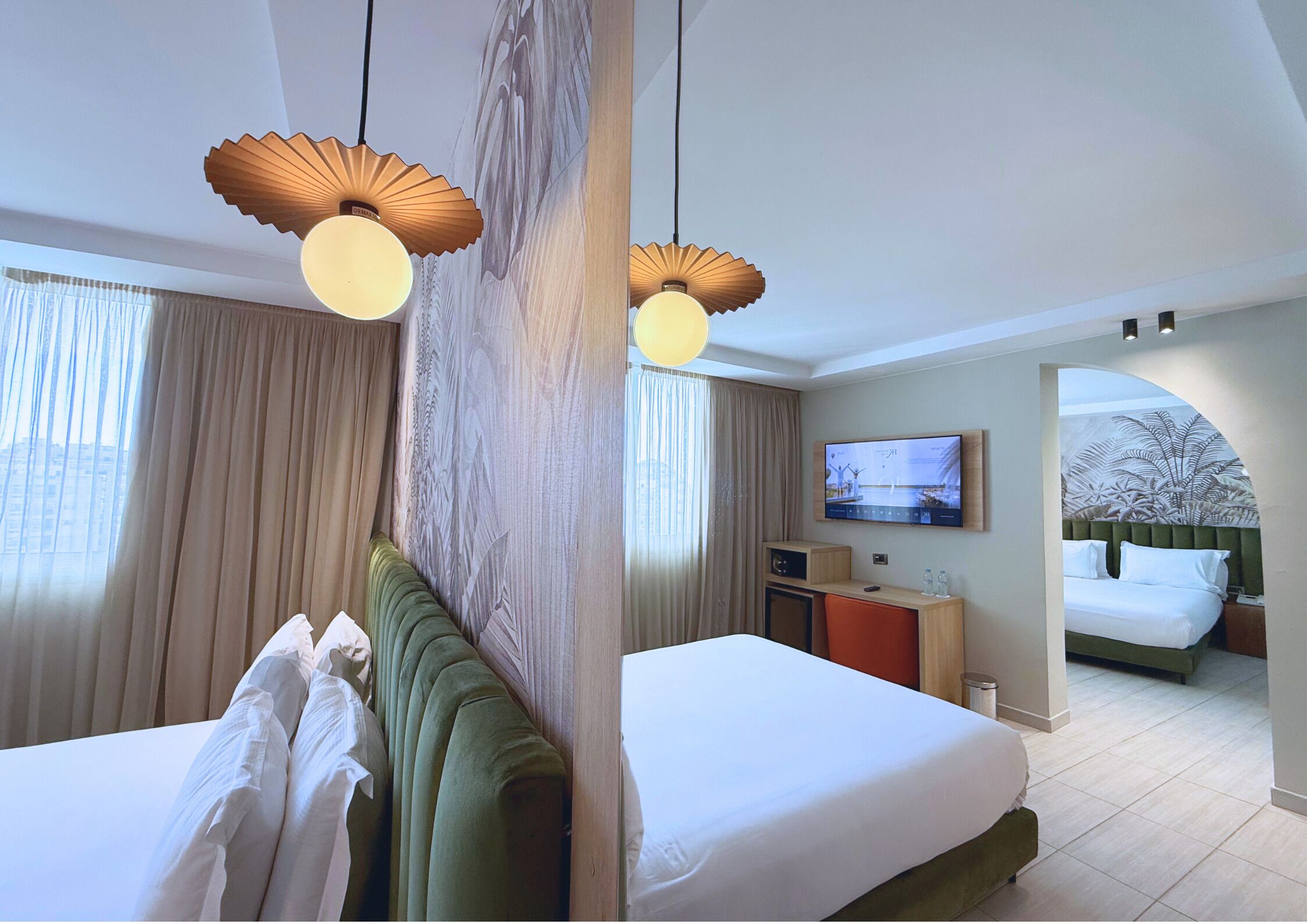 Quarto de hotel com cama grande, escrivaninha, televisão e vista para a cidade.