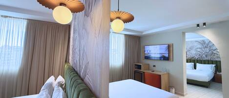 Quarto de hotel com cama grande, escrivaninha, televisão e vista para a cidade.