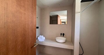 Uma casa de banho moderna com porta de madeira, lavatório branco e espelho em cima.