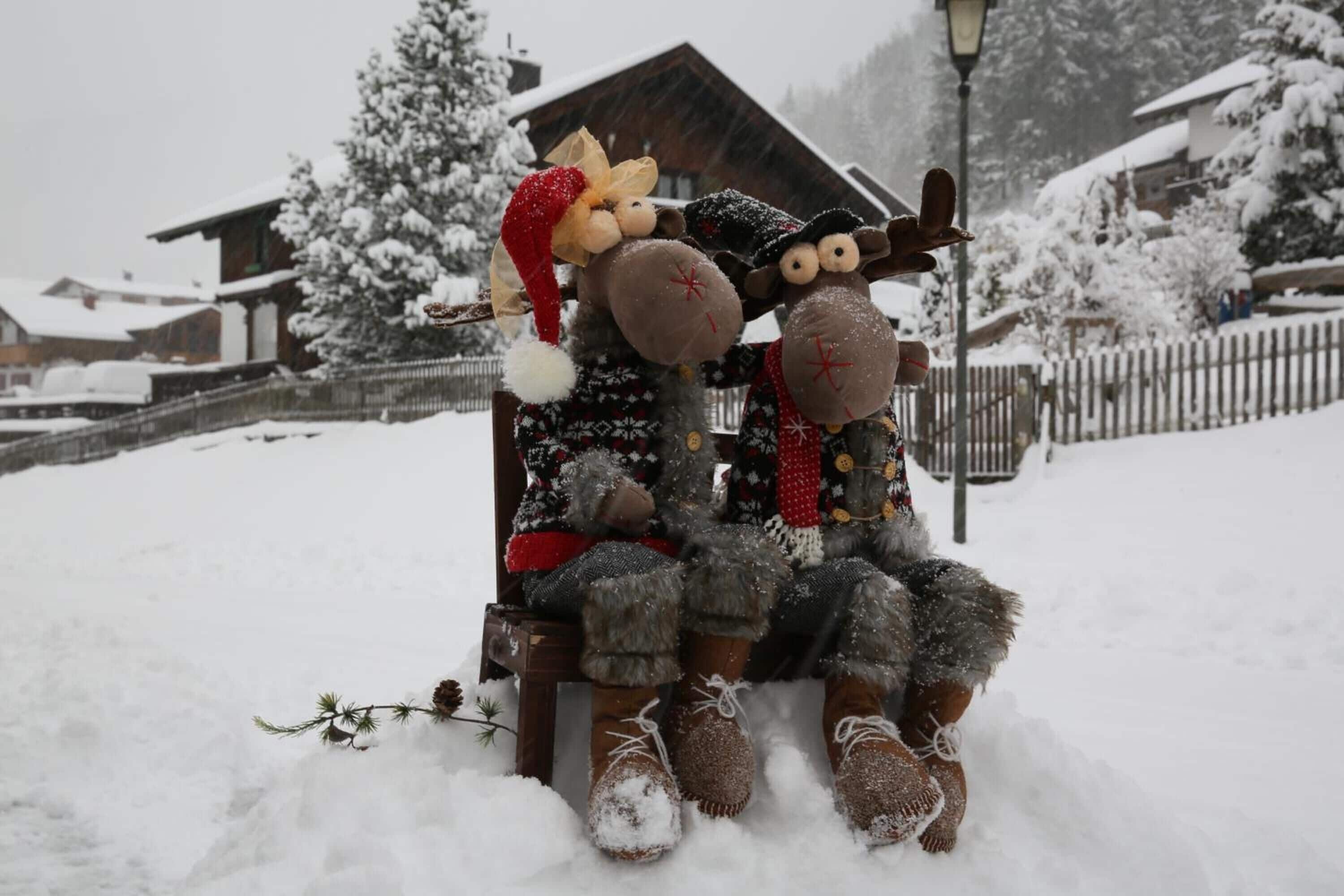 Uma área externa coberta de neve, com um banco de madeira.