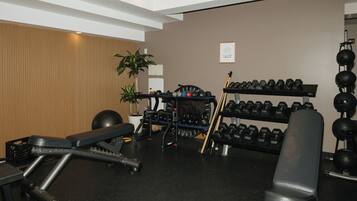 Uma academia com equipamentos de ginástica, halteres e um banco.