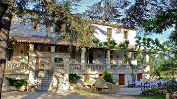 Um edifício de dois andares com varanda, escadaria e área de estar ao ar livre.