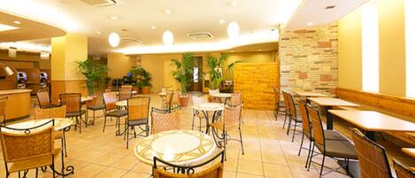 Um restaurante com mesas e cadeiras redondas, plantas em vasos e uma parede de tijolos.