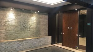 Um lobby moderno com parede de pedra, um banco e um elevador.