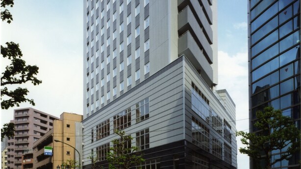 Um hotel moderno com localização de destaque na esquina, grandes janelas e telhado plano.