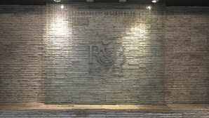 Pareda de pedra texturizada com um nicho contendo um logotipo.