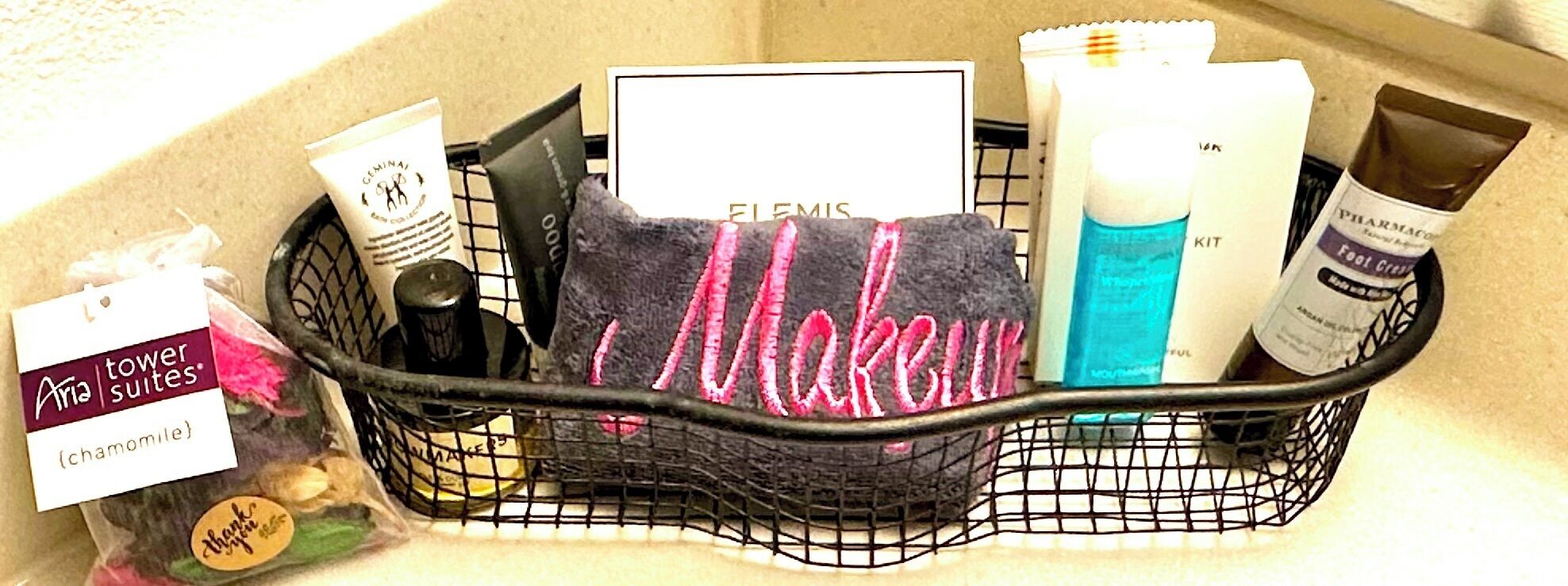 Cesto com produtos de higiene e uma toalha com a palavra 'Makeup'.
