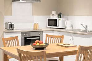 Cozinha moderna com armários brancos, micro-ondas, torradeira e pia.