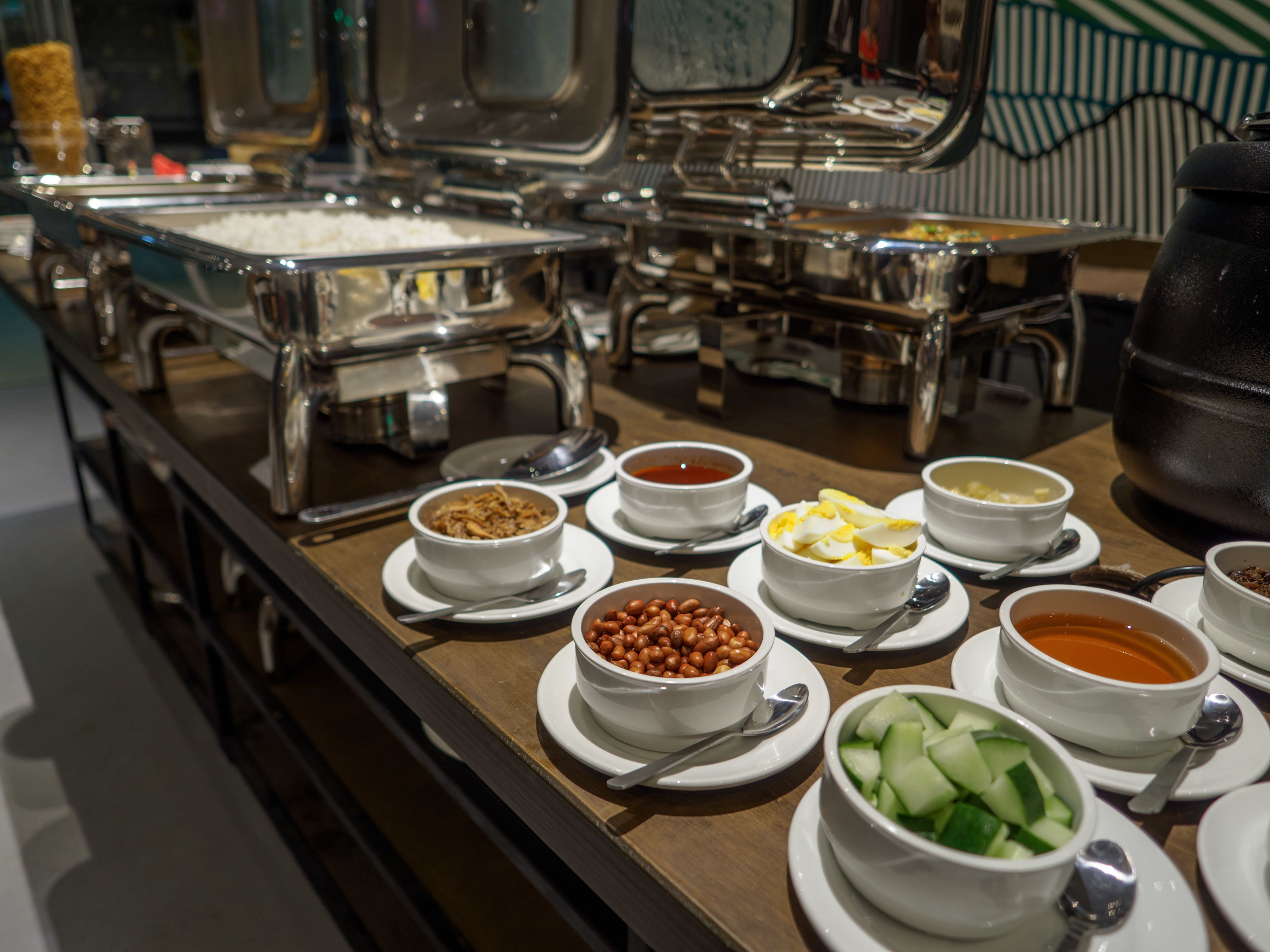 Buffet com diversas opções de comida, incluindo arroz, feijão, ovos e sopa.