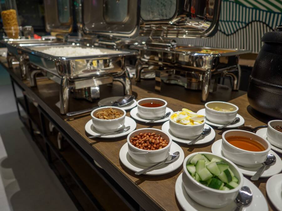 Buffet com diversas opções de comida, incluindo arroz, feijão, ovos e sopa.