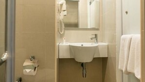 Casa de banho compacta com sanita, lavatório e chuveiro.