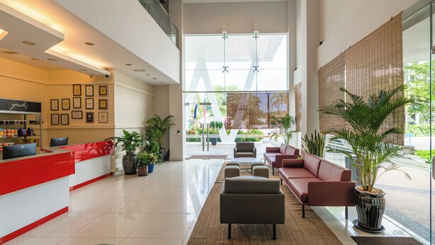 Um hall amplo com balcão de recepção, área de estar e grandes janelas com vista para o exterior.