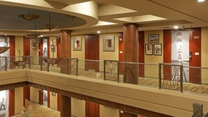 Um lobby de hotel com átrio central, vários andares e guarda-corrimão de vidro.