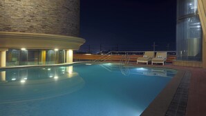 Piscina com espreguiçadeiras e um muro de pedra.