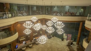 Um hall espaçoso com teto alto, várias luminárias e um balcão de recepção.