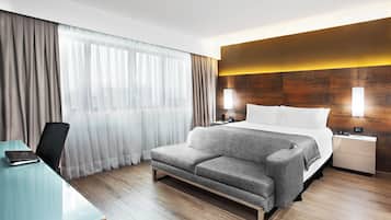 Quarto de hotel moderno com uma cama grande, uma escrivaninha e uma cadeira.