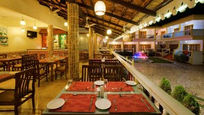 Restaurante com mesas e cadeiras de madeira, varanda com vista para o pátio e estilo arquitetônico tradicional.