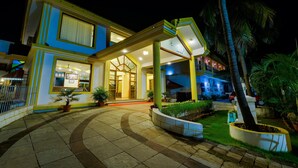 Um hotel de dois andares com uma entrada bem iluminada e uma área externa coberta.