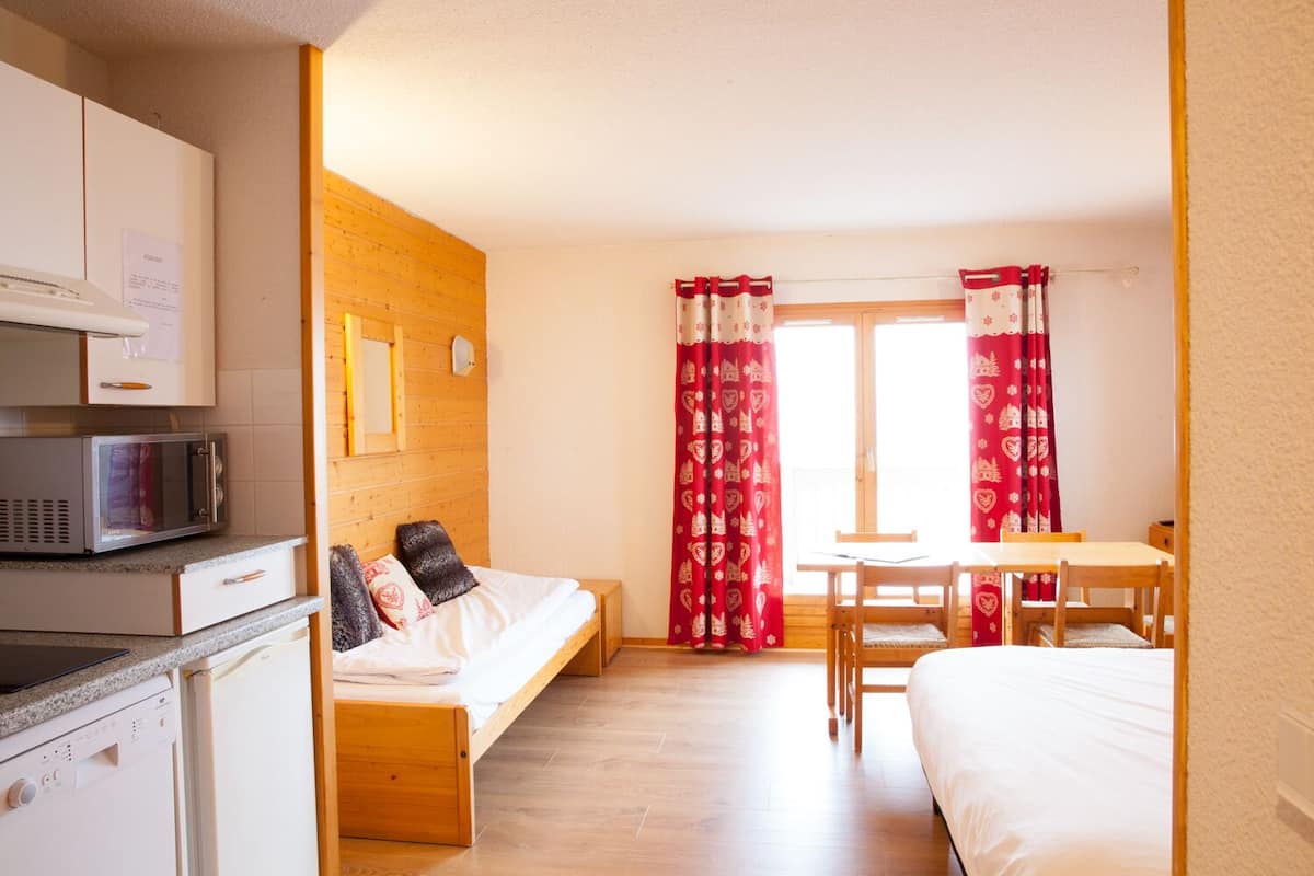 Quarto compacto com uma cama, uma secretária pequena, micro-ondas e máquina de lavar.