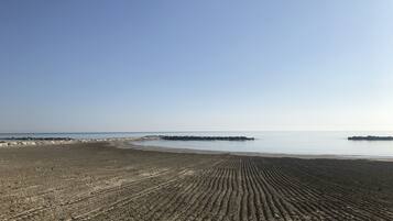 Praia particular, areia branca, espreguiçadeiras, guarda-sóis