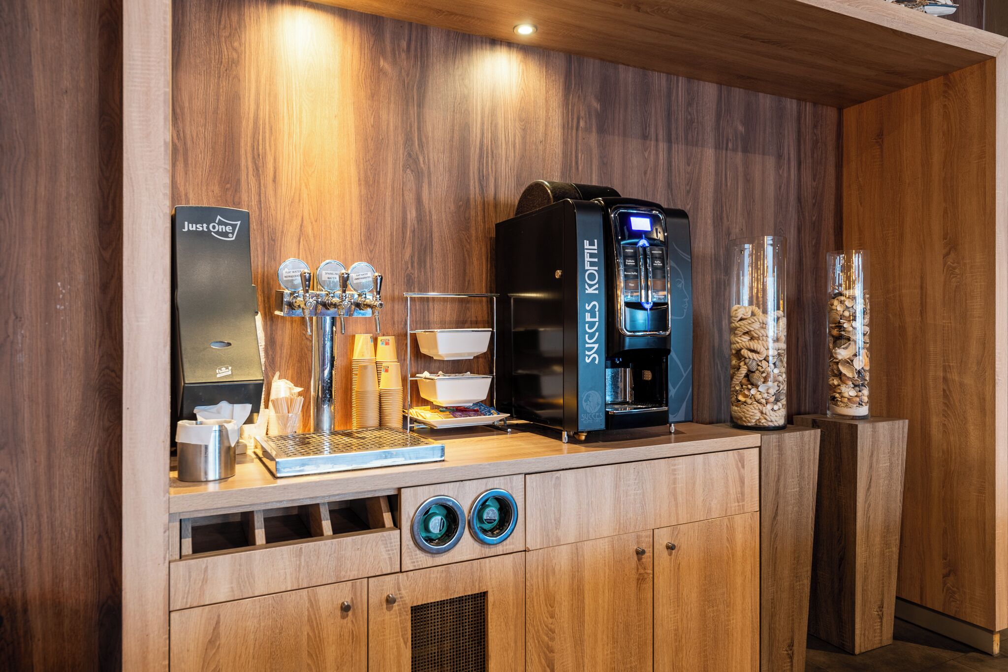 Estação de café com máquina de espresso da marca, várias torneiras e dispensador de café.