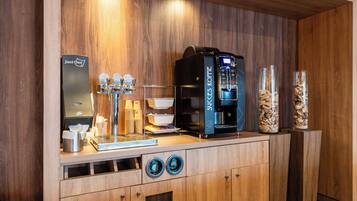 Estação de café com máquina de espresso da marca, várias torneiras e dispensador de café.