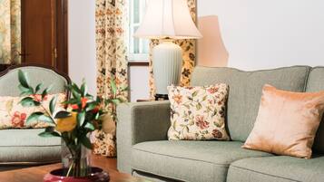 Uma sala de estar com um sofá, uma mesa com um vaso de flores e um abajur.